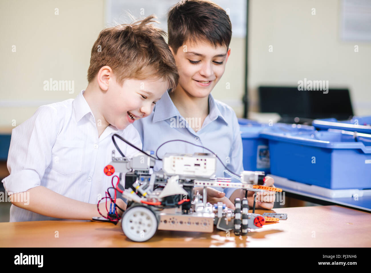 Two brothers kids playing with robot toy at school robotics class ...