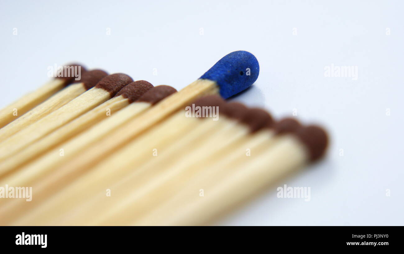 Brown matches with one blue match in the middle on white background ...