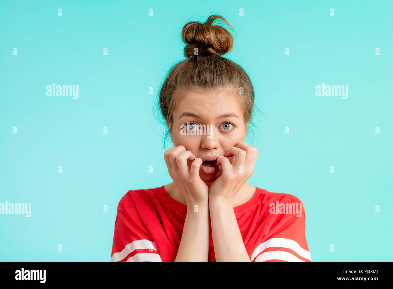 close up portrait of a beautiful fearful girl with fingers on her mouth ...