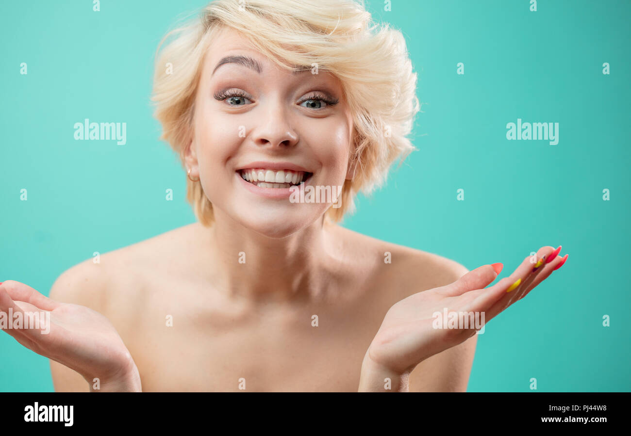 Smiling blond woman showing open hand palm Stock Photo - Alamy
