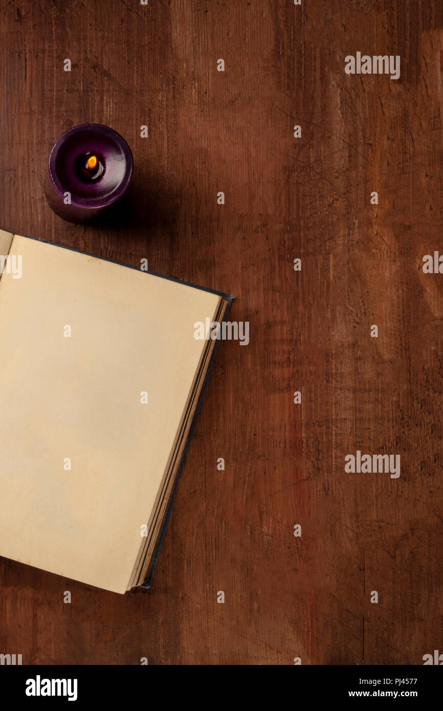 An old book with a candle on a dark rustic background with copy space ...