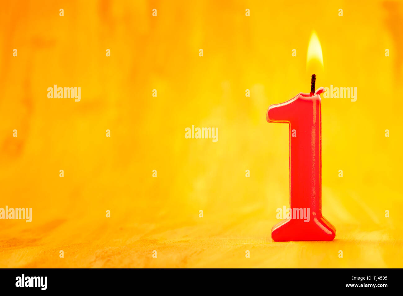 Red number one burning candle on a golden background with copyspace ...