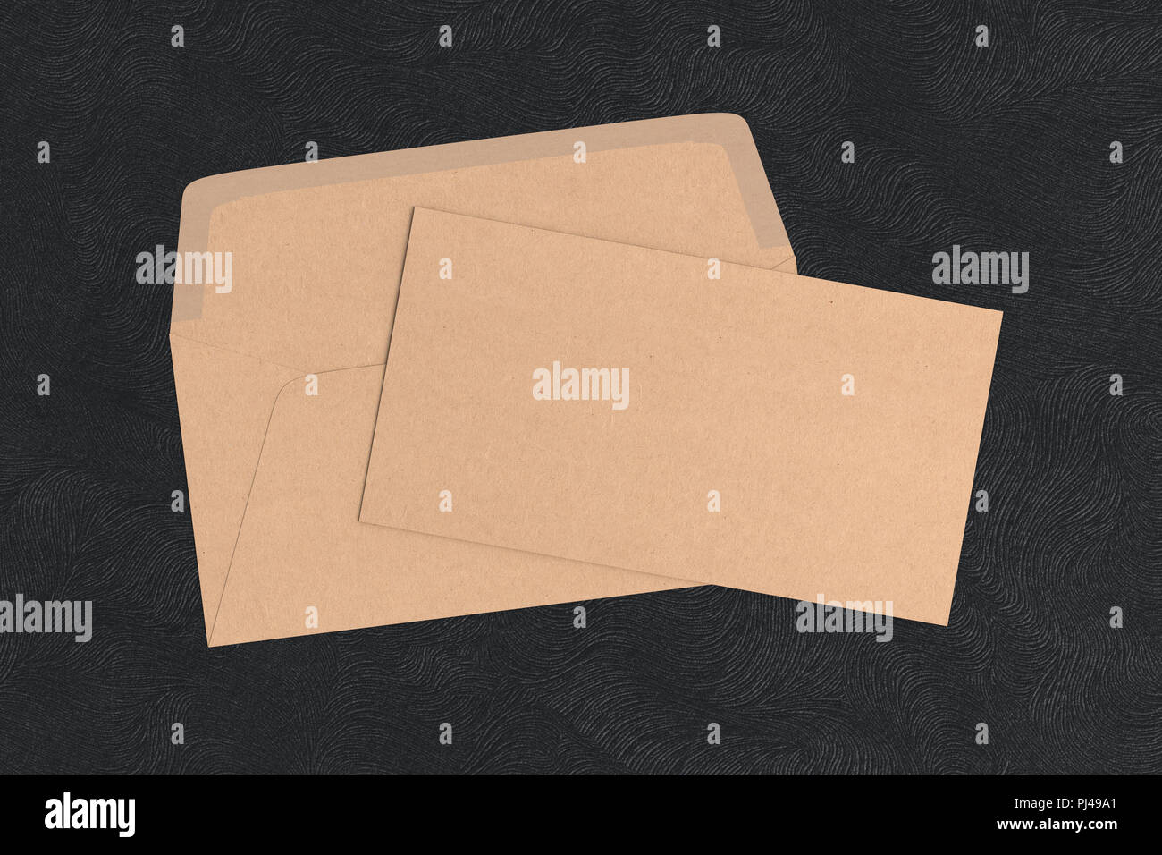 Craft paper blank closed envelope on opened envelope on black ...