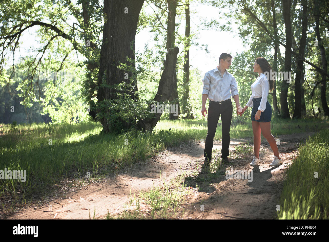 young couple walking in the forest, summer nature, bright sunlight ...