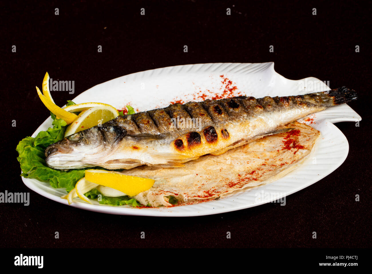 Roasted seabass fish served lemon Stock Photo - Alamy