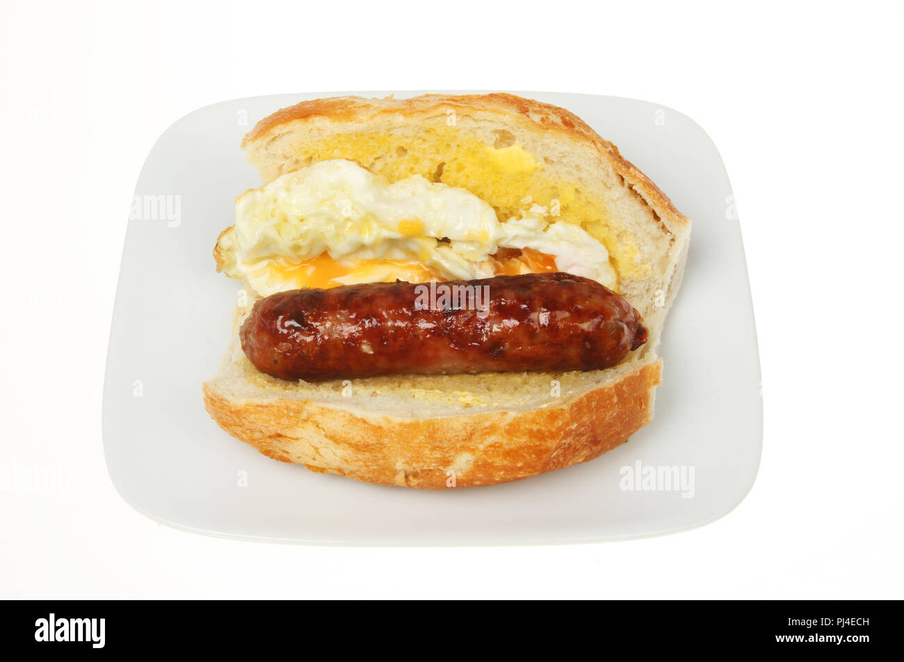 Fried egg and sausage in a giraffe bread roll on a plate isolated ...
