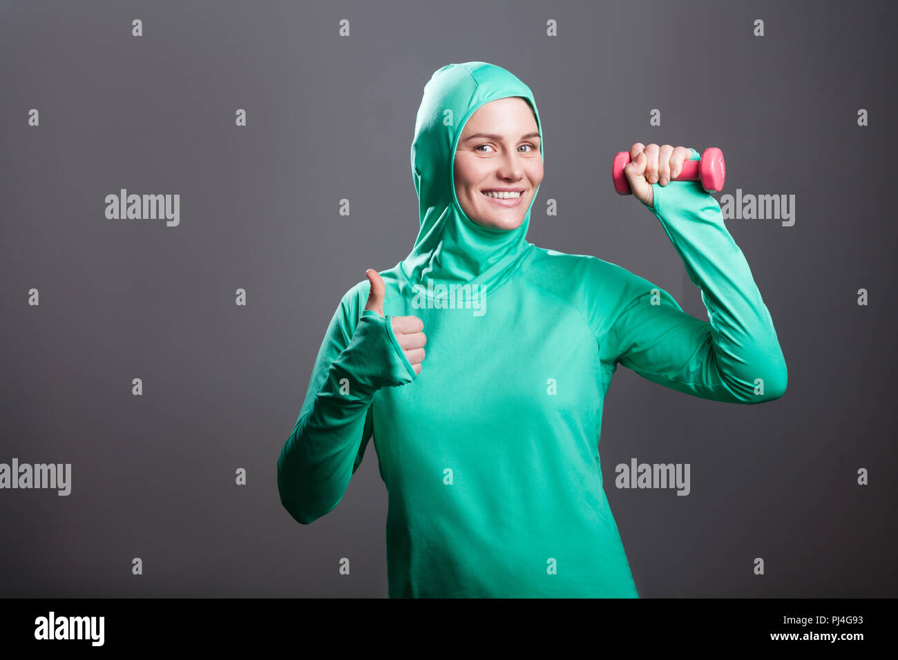 Satisfied muslim woman in green hijab or islamic sport wear standing ...