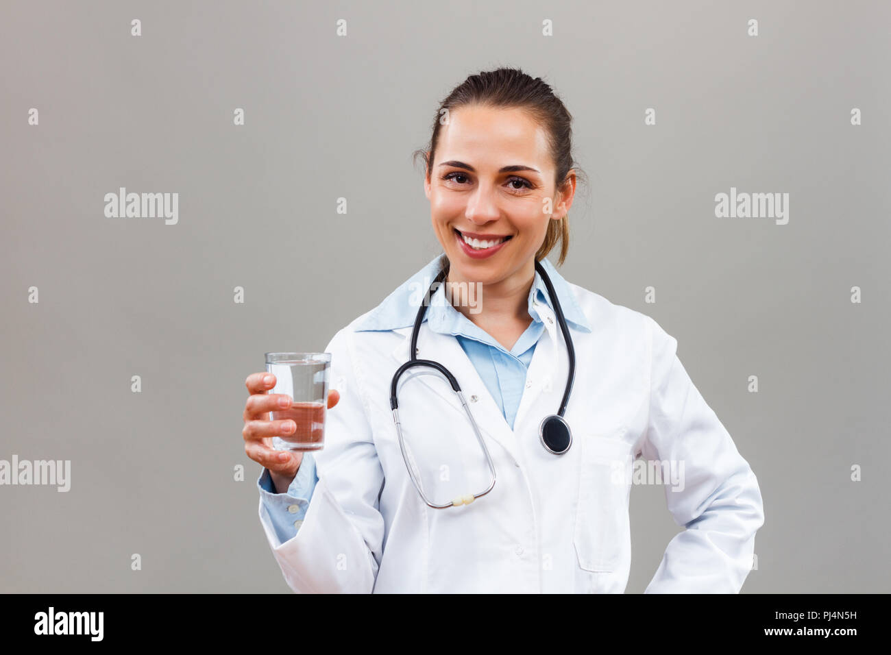Beautiful female doctor holding glass of water Stock Photo - Alamy