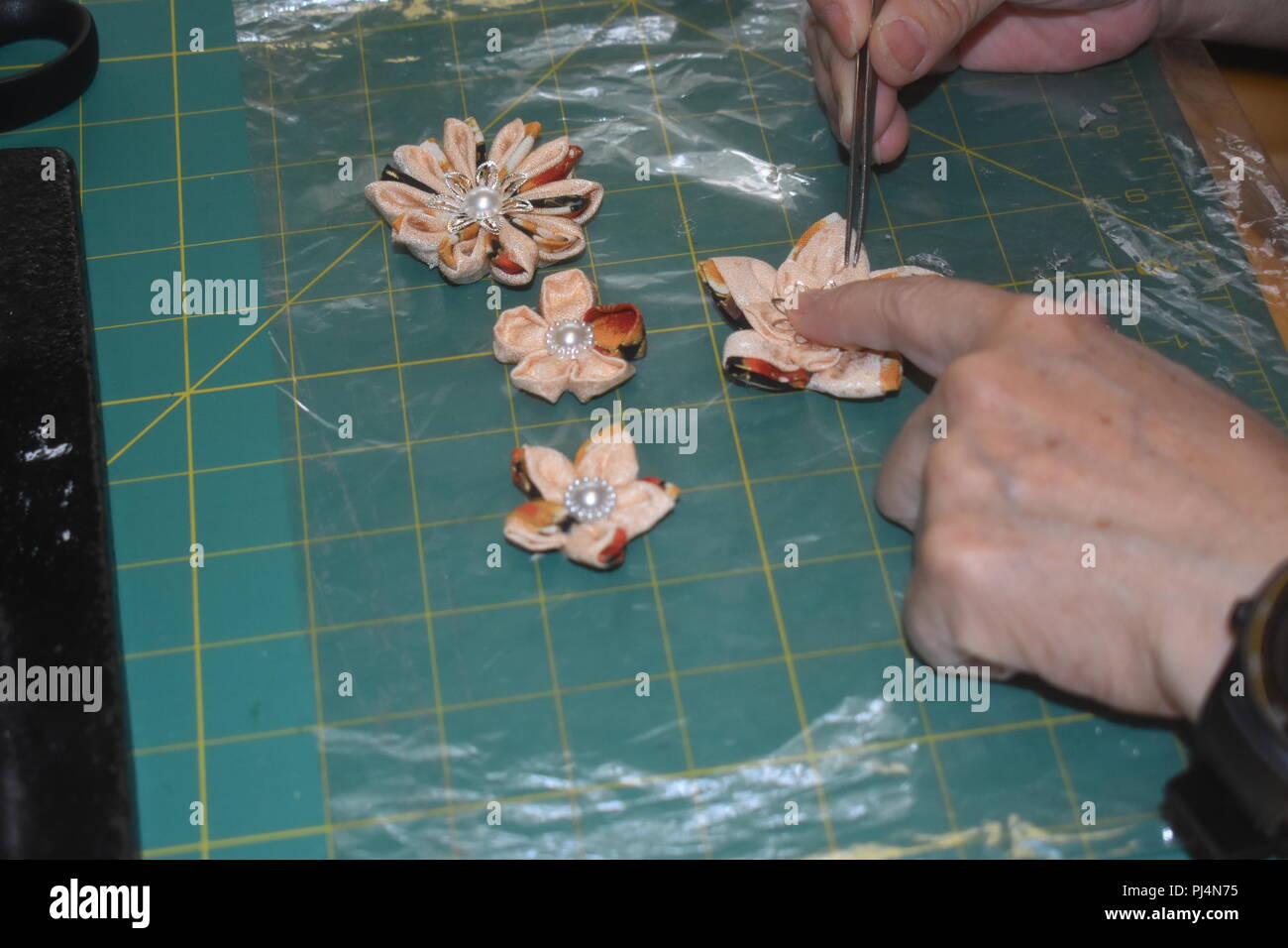 Woman's hands putting final touches on handmade Kanzashi ornamental ...