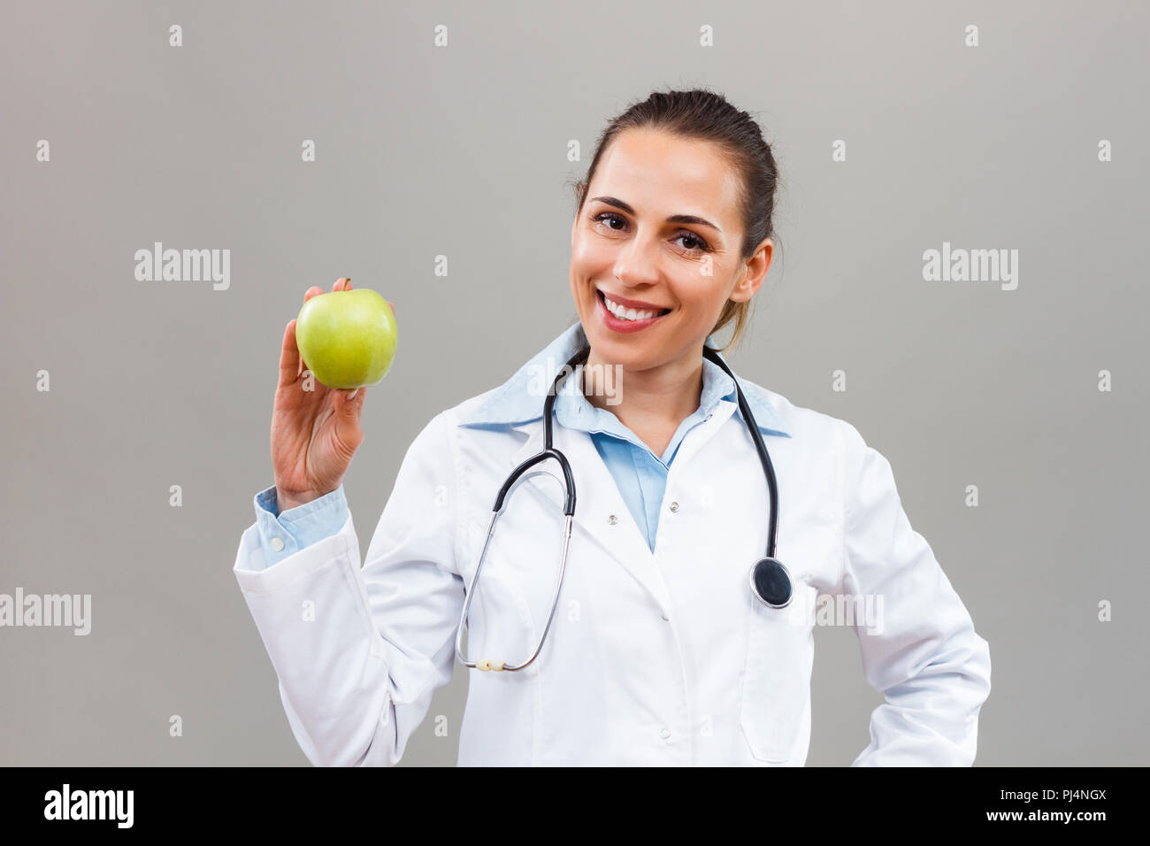 Beautiful female doctor is showing apple and remind us how is important ...