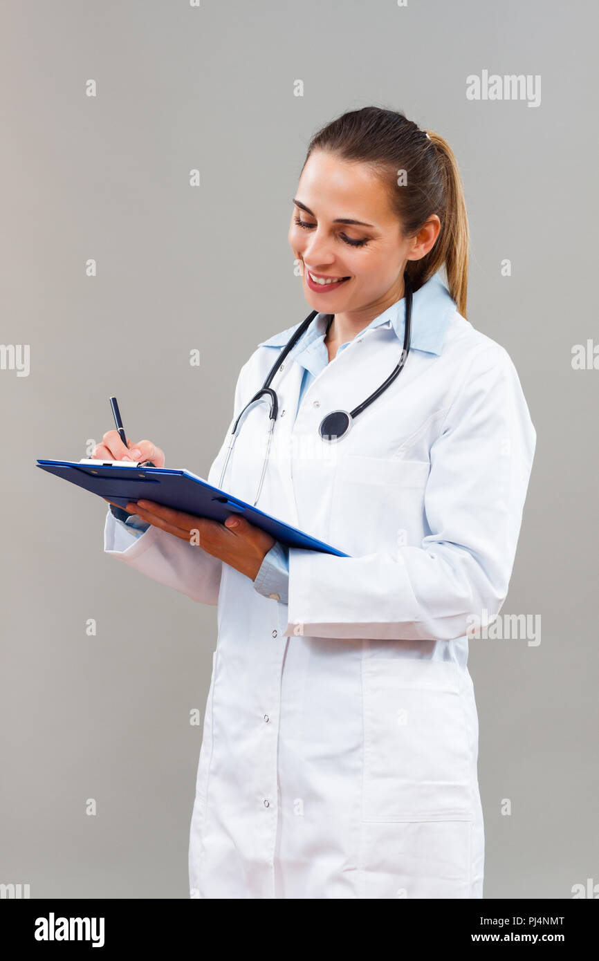 Beautiful female doctor writing notes Stock Photo - Alamy
