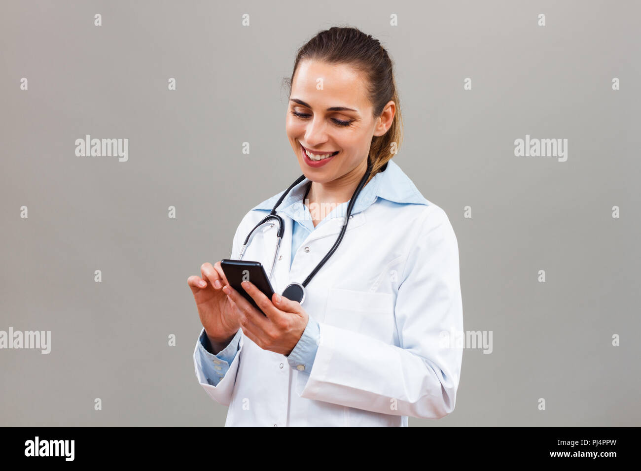 Beautiful female doctor texting messages on mobile phone Stock Photo ...