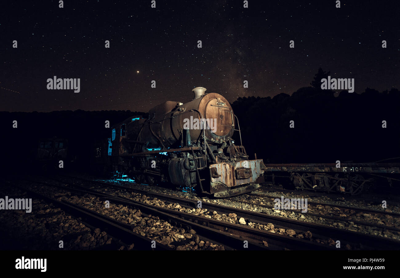 Old locomotive with blue light and Milky way above it in the old train ...