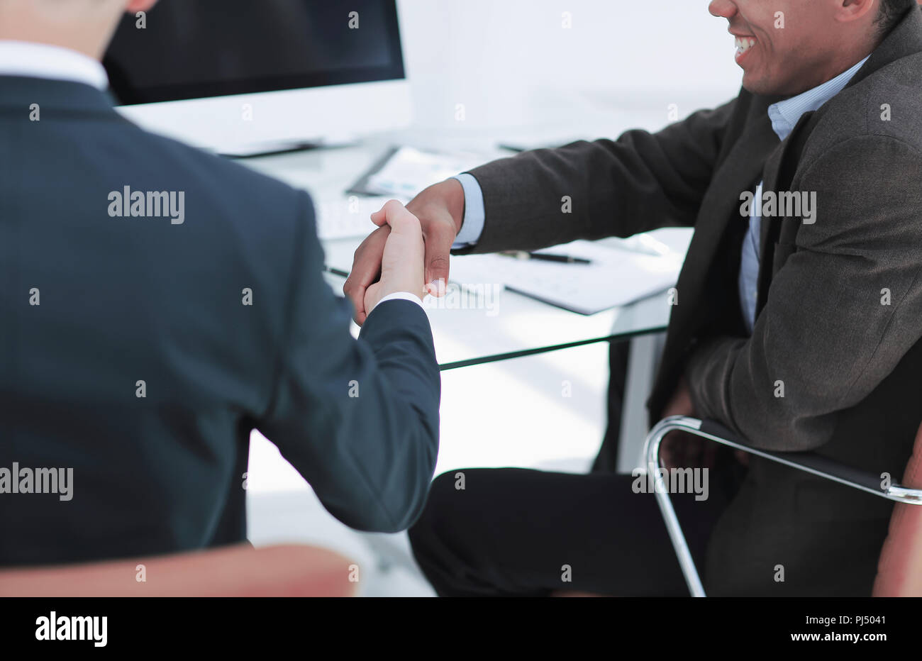 rear view.the handshake between colleagues in the workplace Stock Photo ...