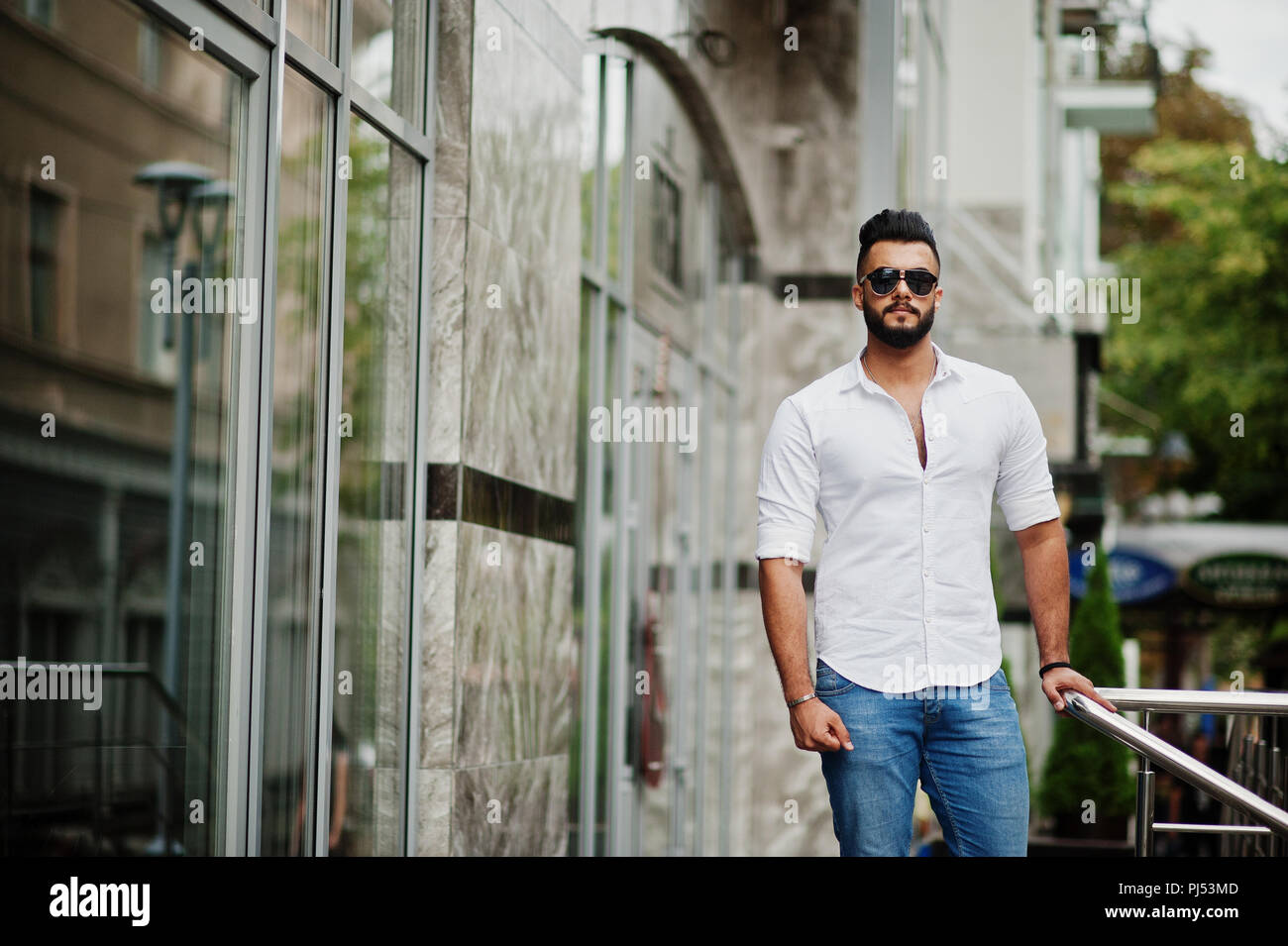 Stylish tall arabian man model in white shirt, jeans and sunglasses ...