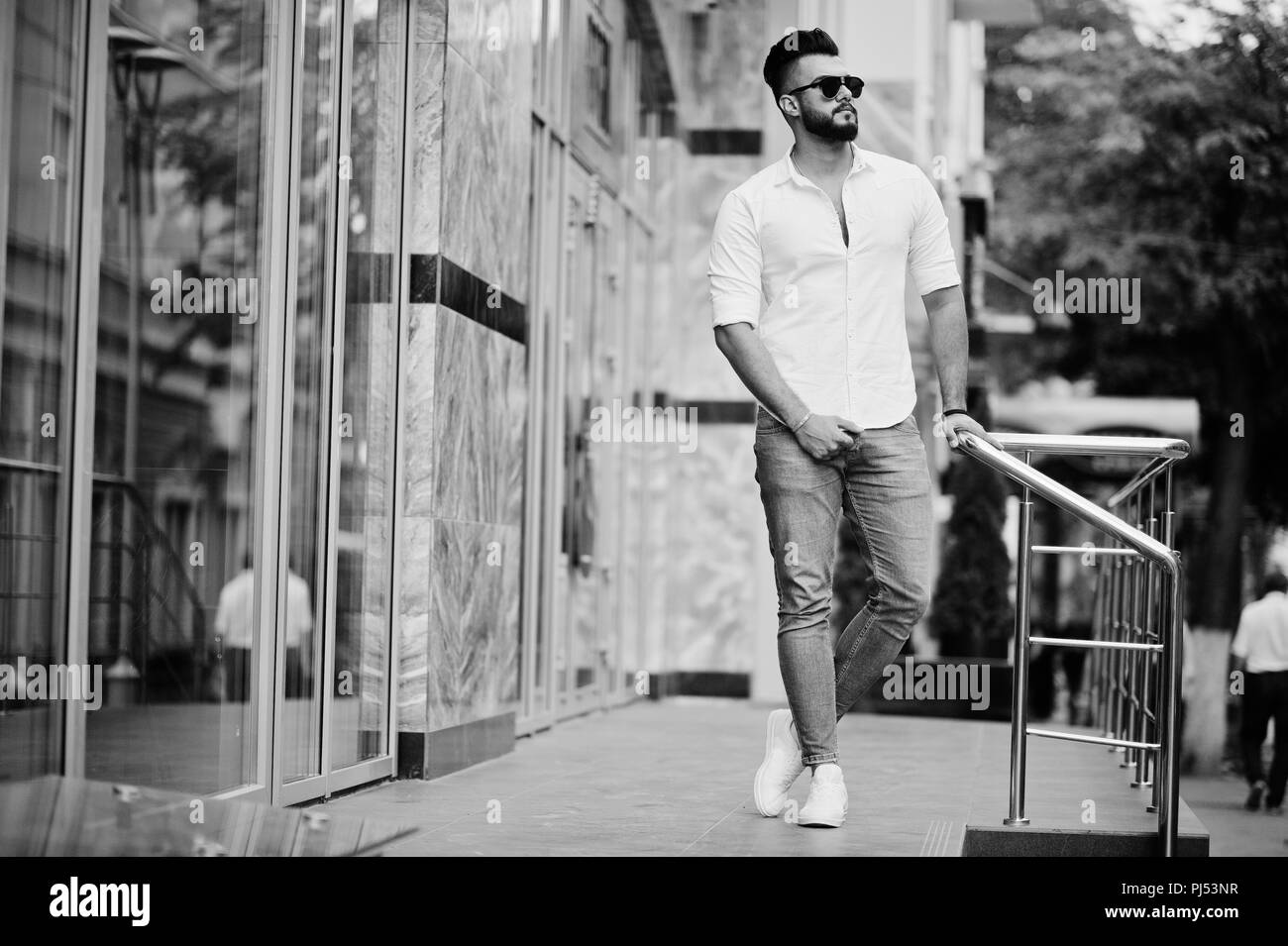 Stylish tall arabian man model in white shirt, jeans and sunglasses ...