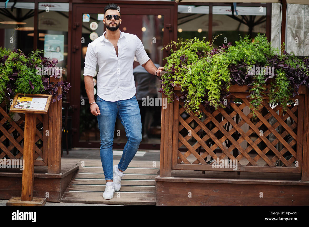 Stylish tall arabian man model in white shirt, jeans and sunglasses ...