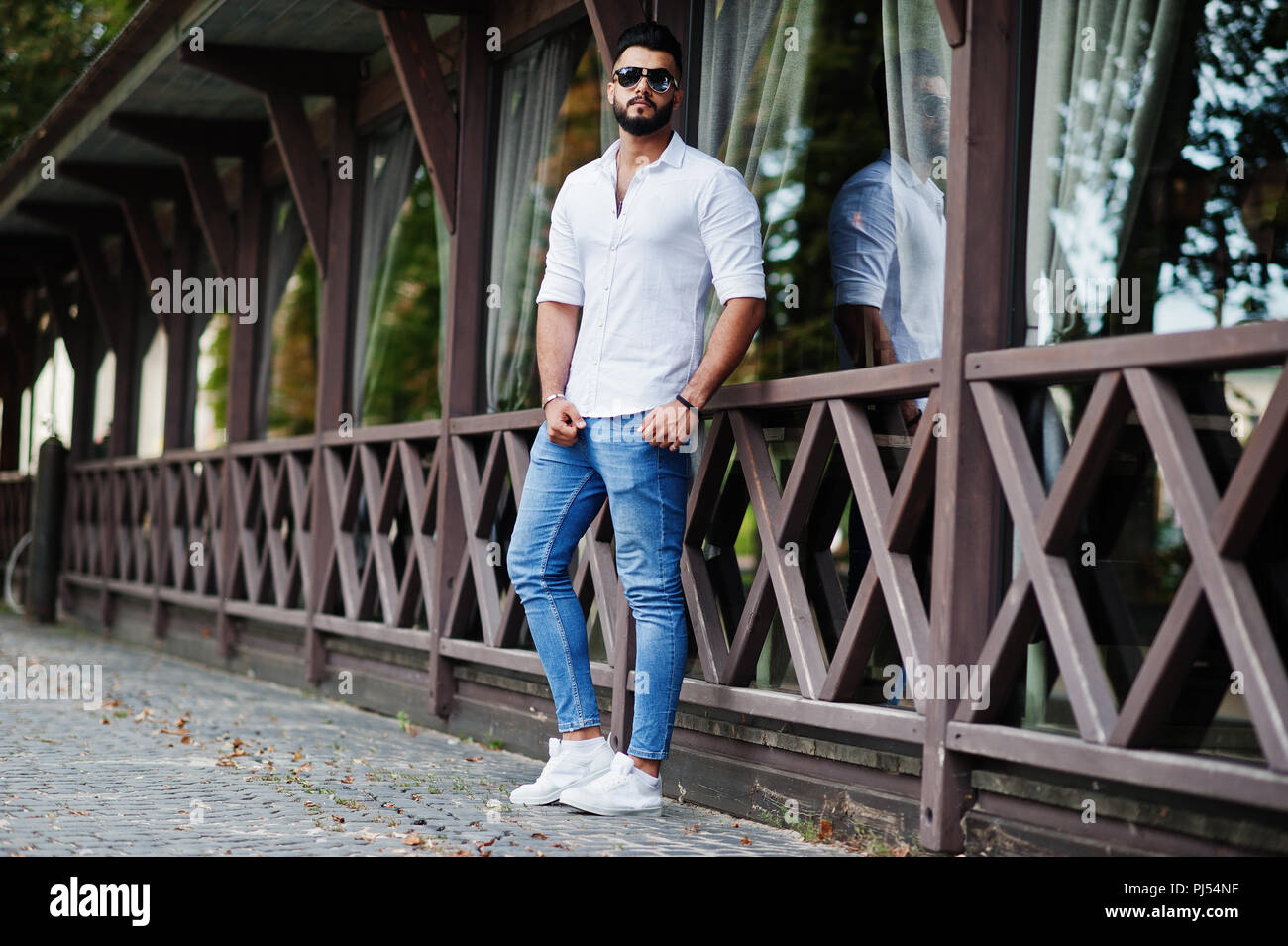 Stylish tall arabian man model in white shirt, jeans and sunglasses ...