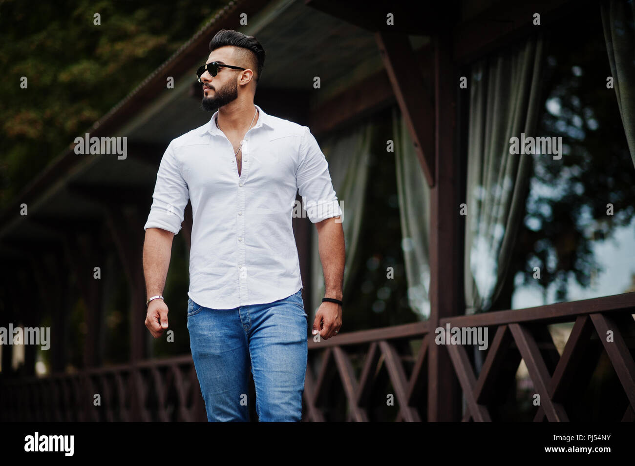 Stylish tall arabian man model in white shirt, jeans and sunglasses ...