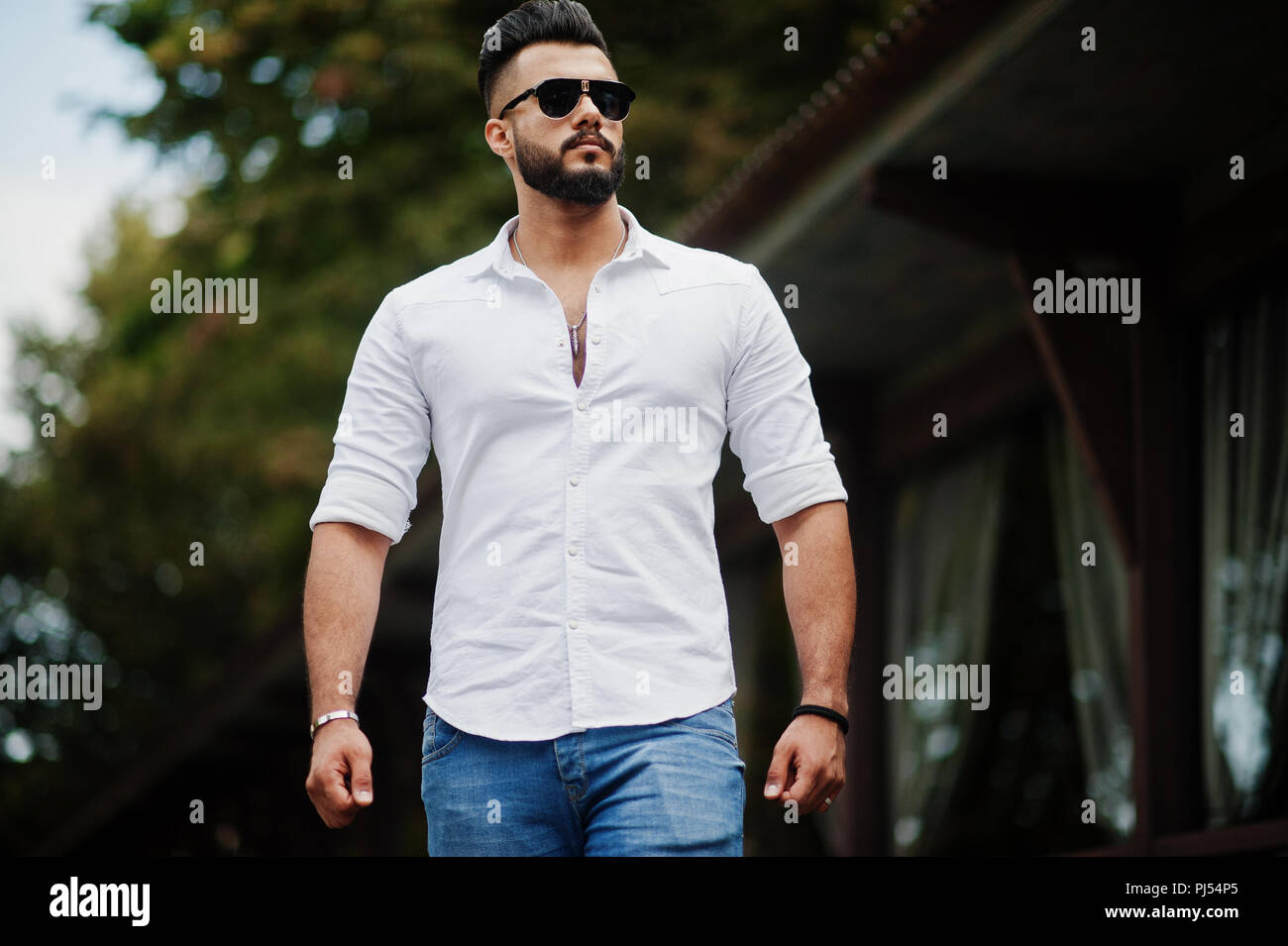 Stylish tall arabian man model in white shirt, jeans and sunglasses ...