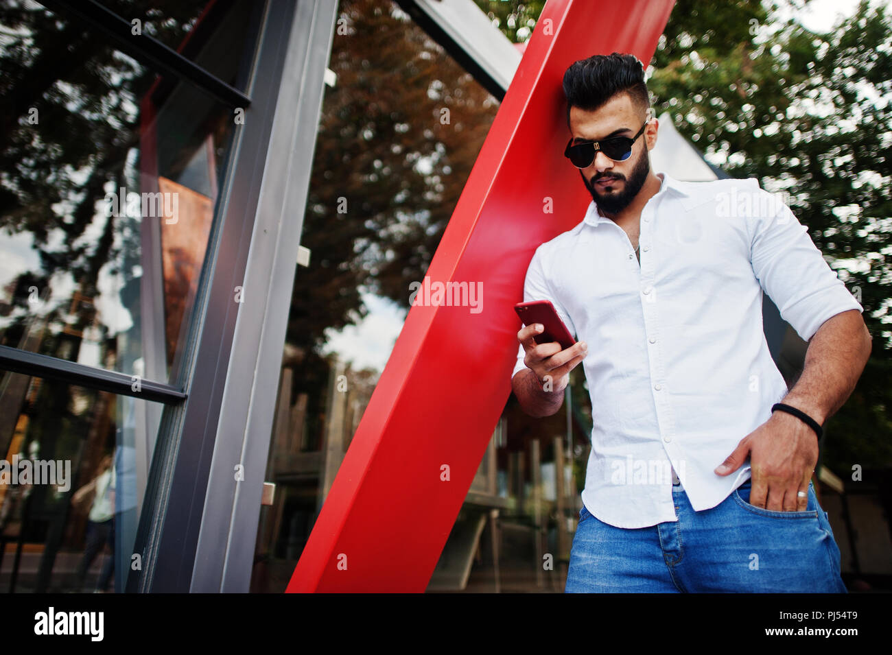 Stylish tall arabian man model in white shirt, jeans and sunglasses ...