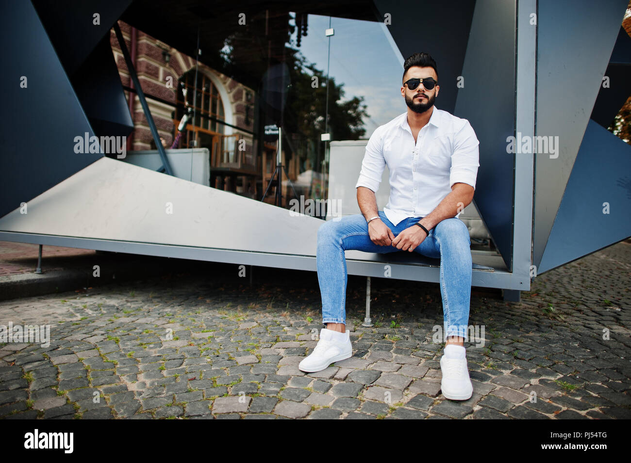 Stylish tall arabian man model in white shirt, jeans and sunglasses ...