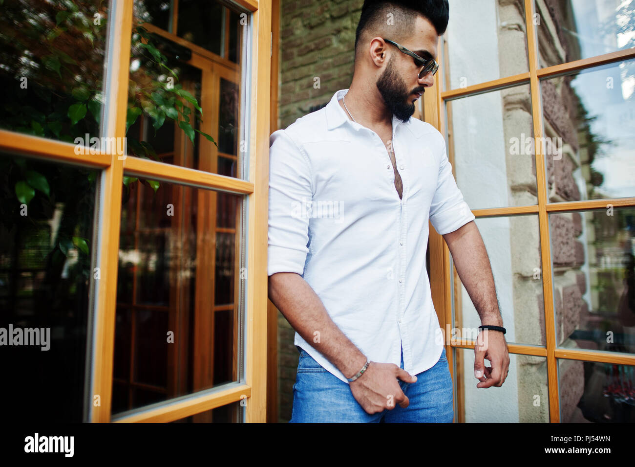 Stylish tall arabian man model in white shirt, jeans and sunglasses ...