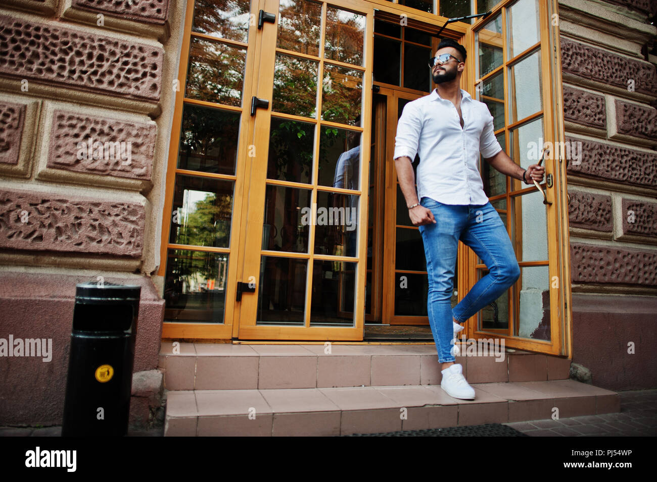 Stylish tall arabian man model in white shirt, jeans and sunglasses ...