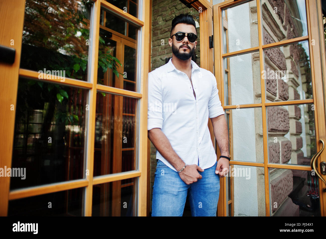 Stylish tall arabian man model in white shirt, jeans and sunglasses ...