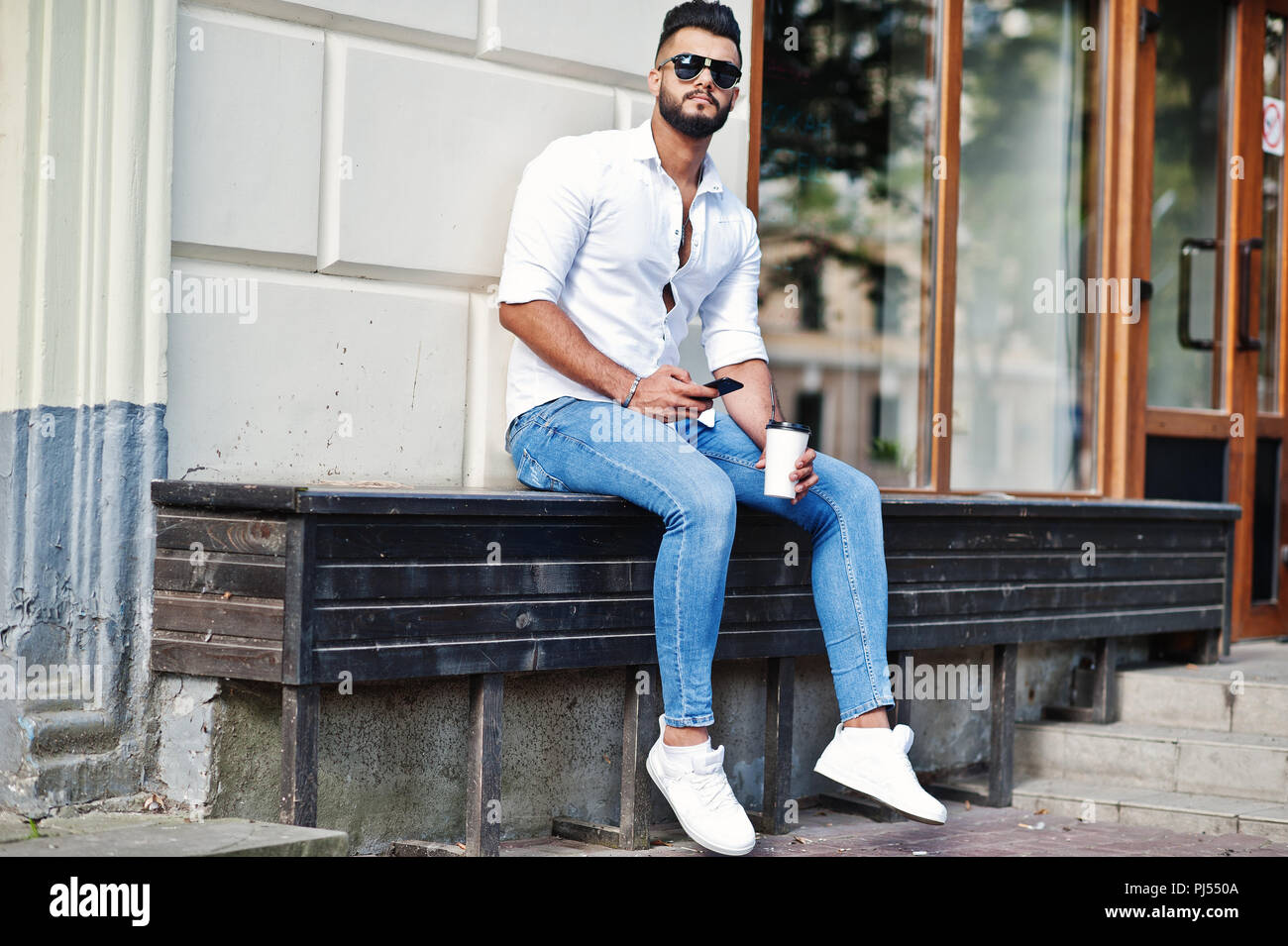 Stylish tall arabian man model in white shirt, jeans and sunglasses ...