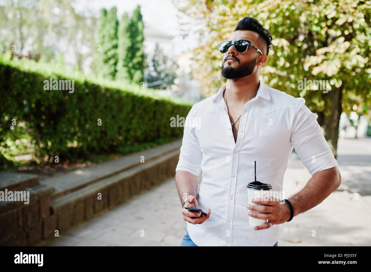 Stylish tall arabian man model in white shirt, jeans and sunglasses ...