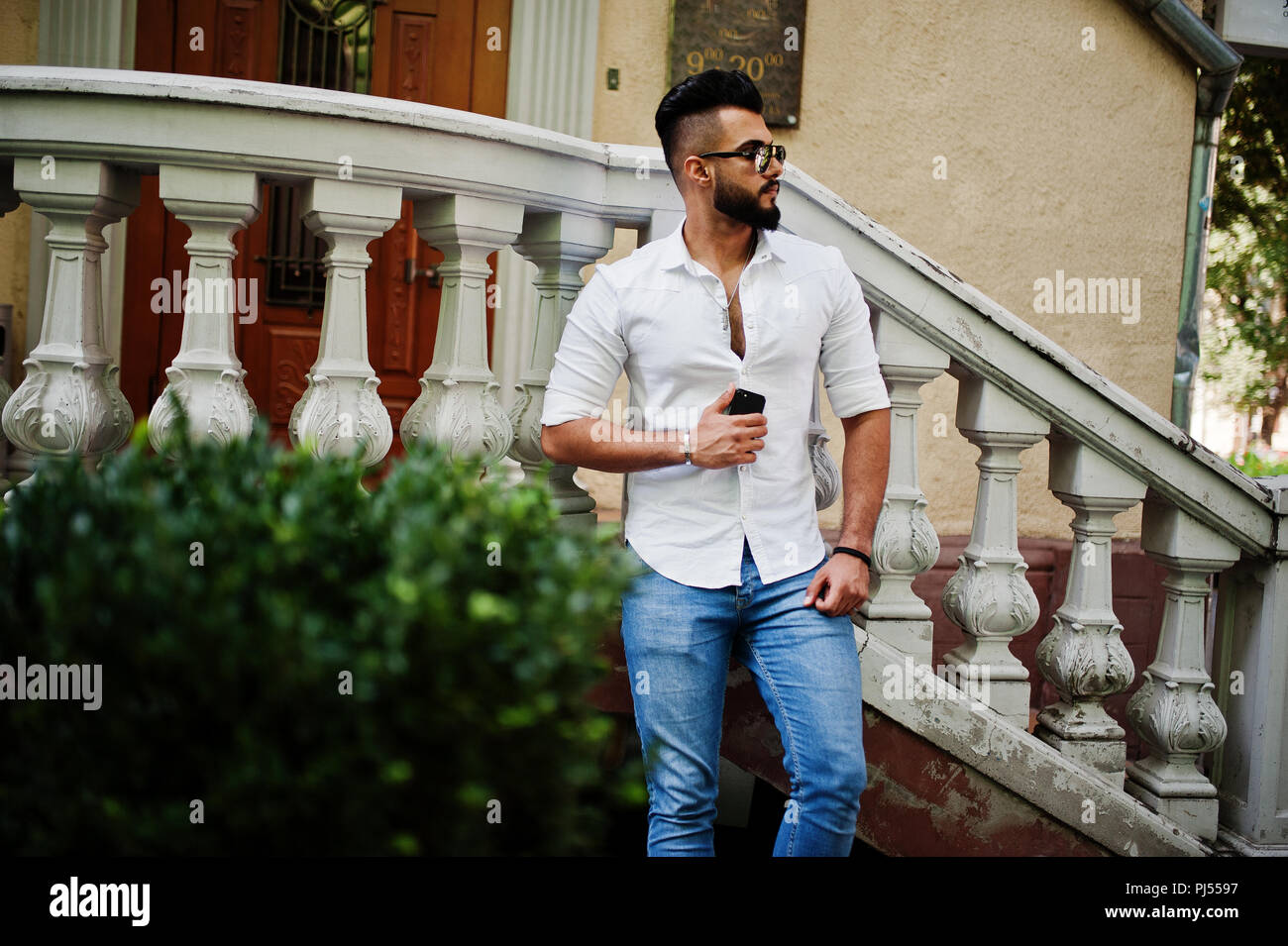 Stylish tall arabian man model in white shirt, jeans and sunglasses ...