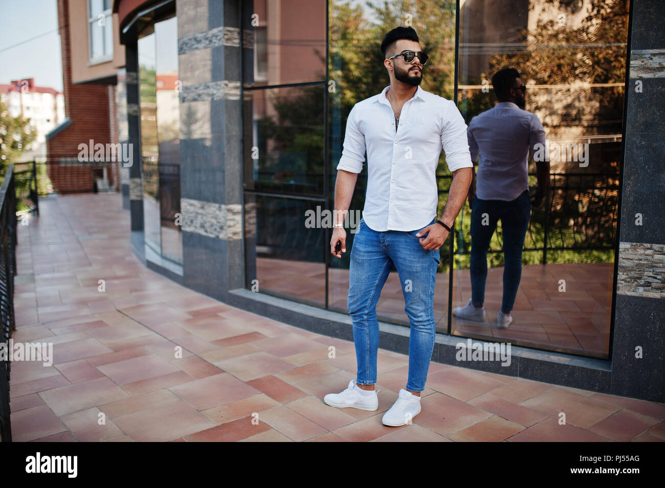 Stylish tall arabian man model in white shirt, jeans and sunglasses ...