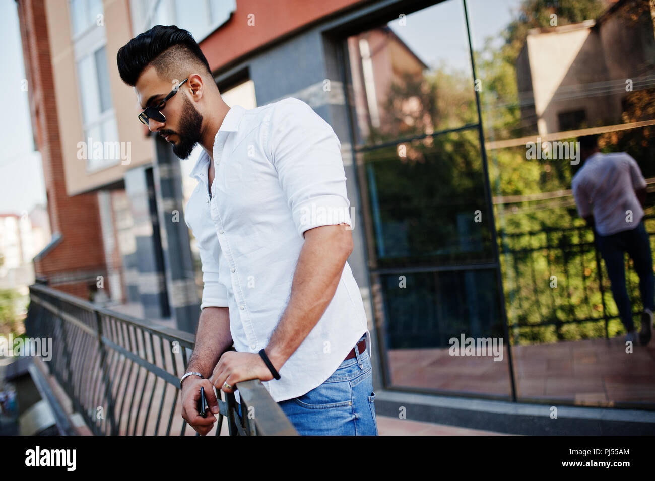 Stylish tall arabian man model in white shirt, jeans and sunglasses ...