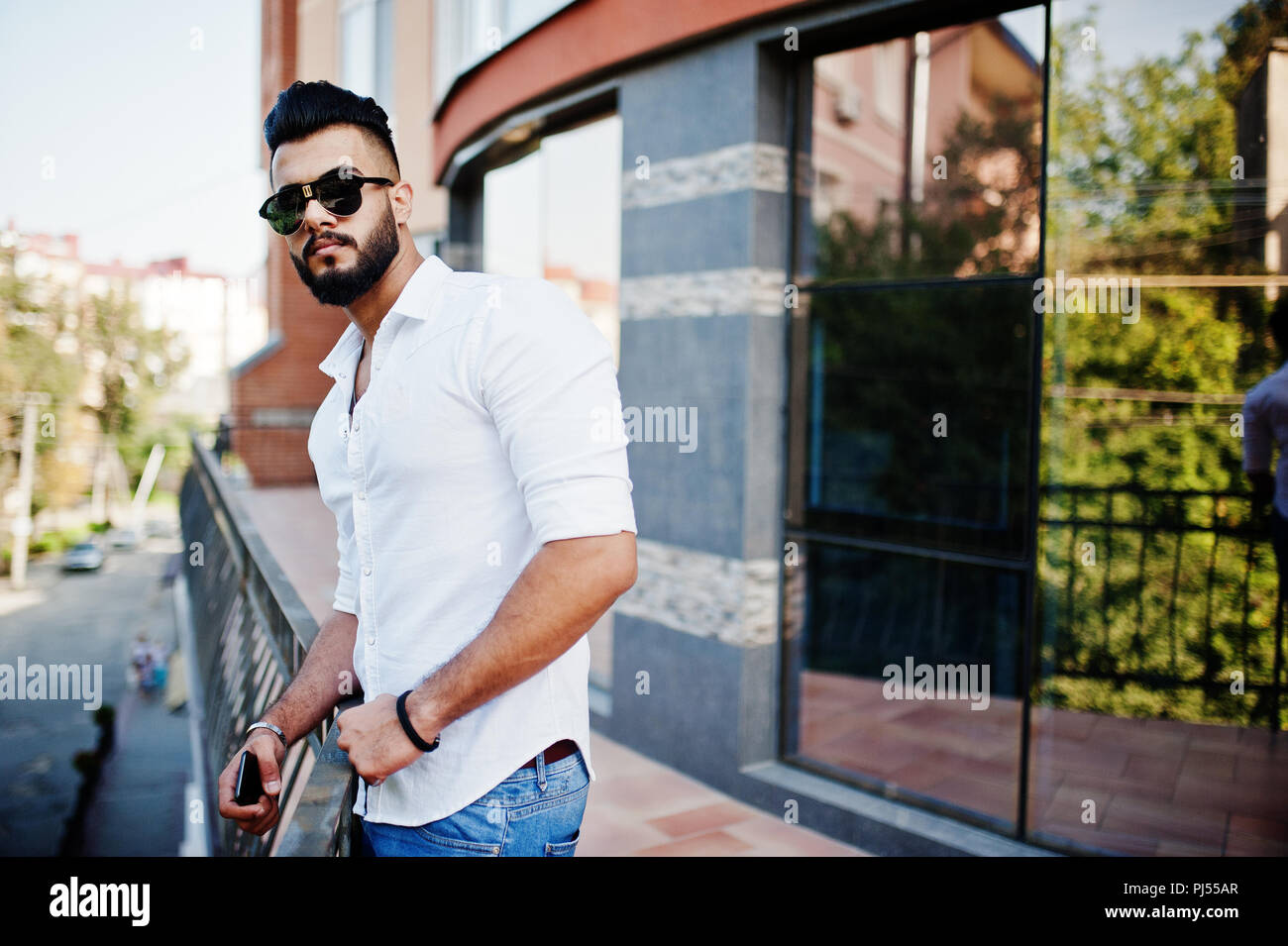 Stylish tall arabian man model in white shirt, jeans and sunglasses ...