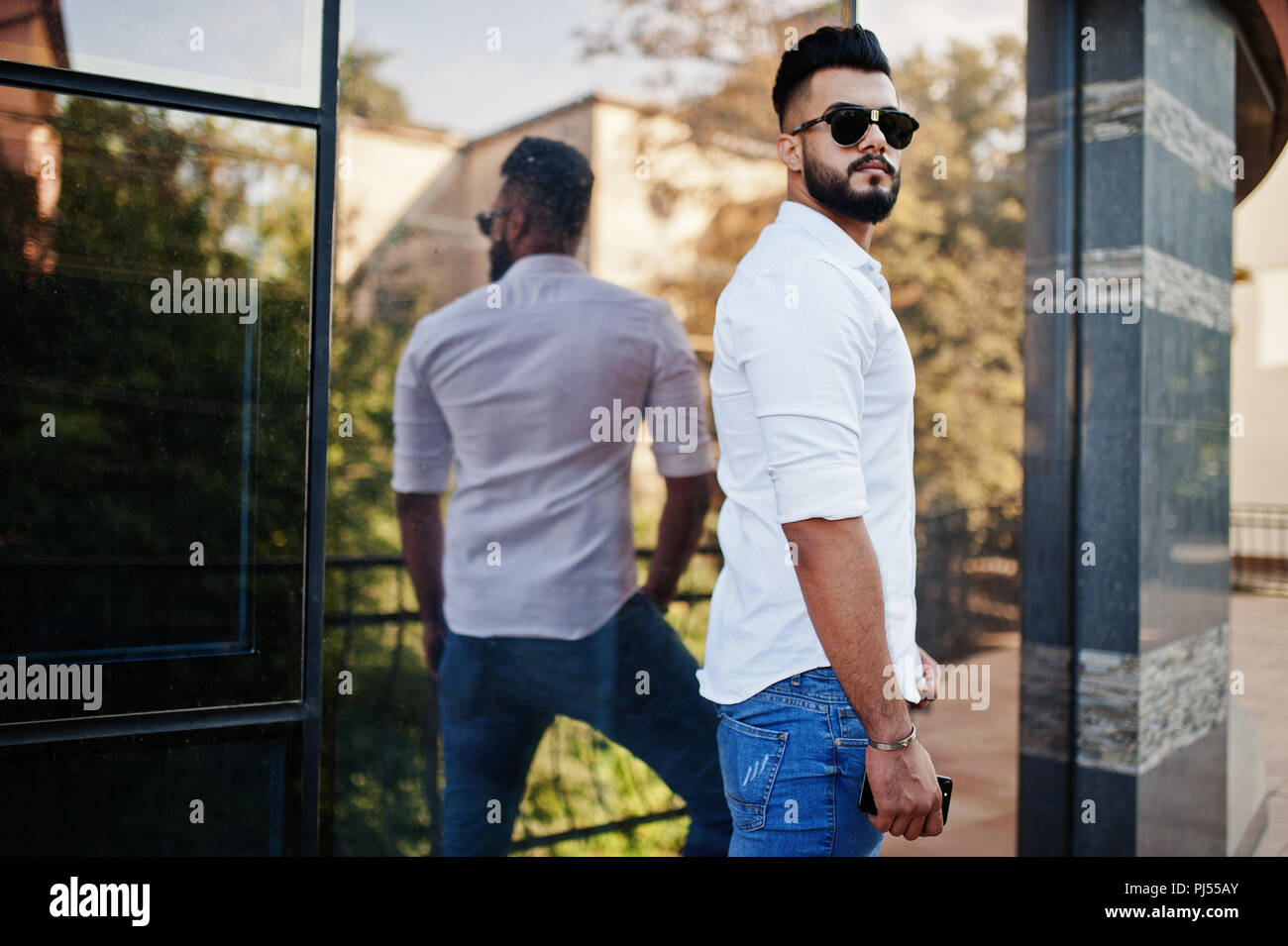 Stylish tall arabian man model in white shirt, jeans and sunglasses ...