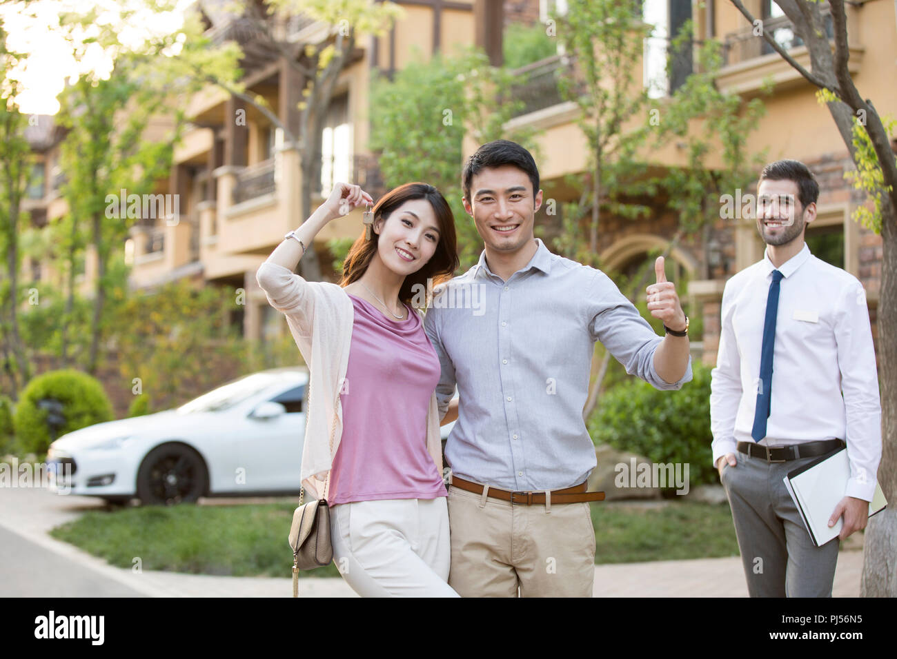 Happy young couple receiving house key from real estate agent Stock ...