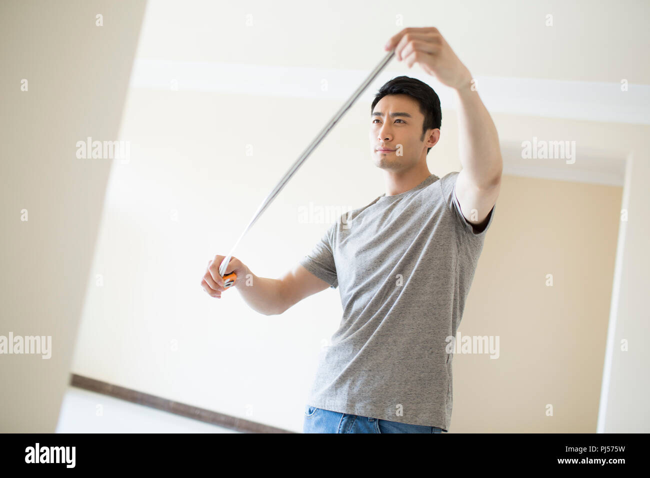 Young man measuring wall Stock Photo - Alamy