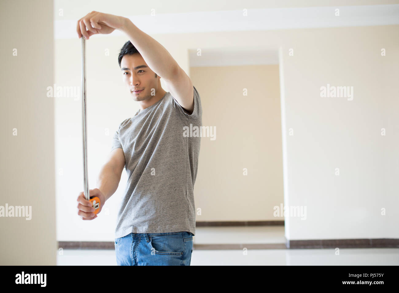 Young man measuring wall Stock Photo - Alamy