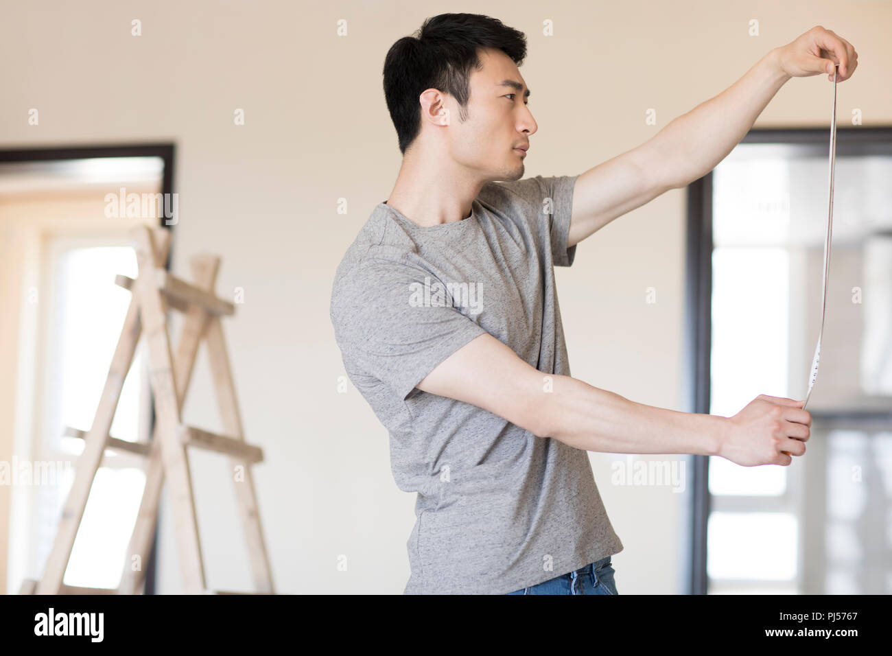 Young man measuring wall Stock Photo - Alamy