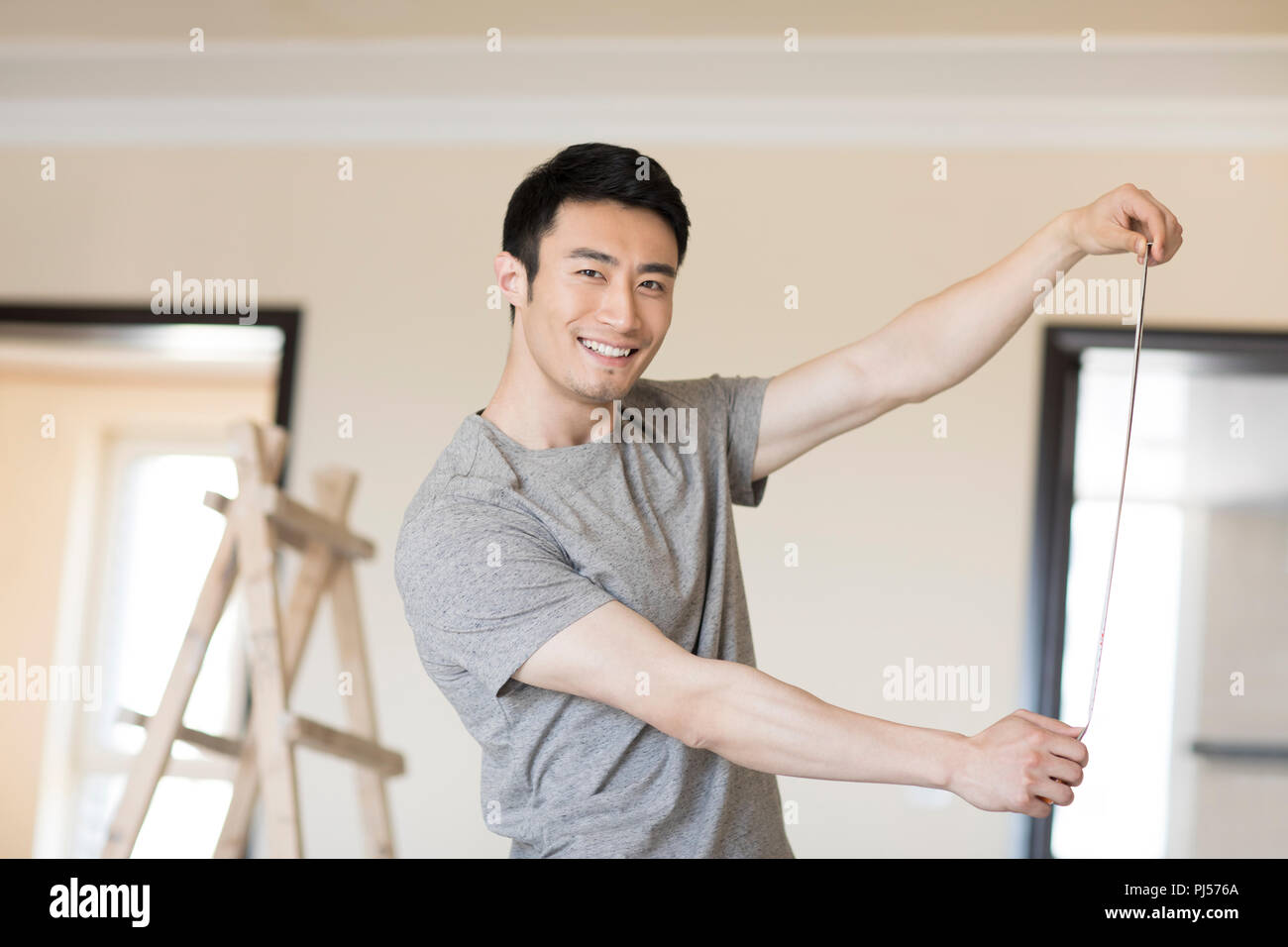 Young man measuring wall Stock Photo - Alamy