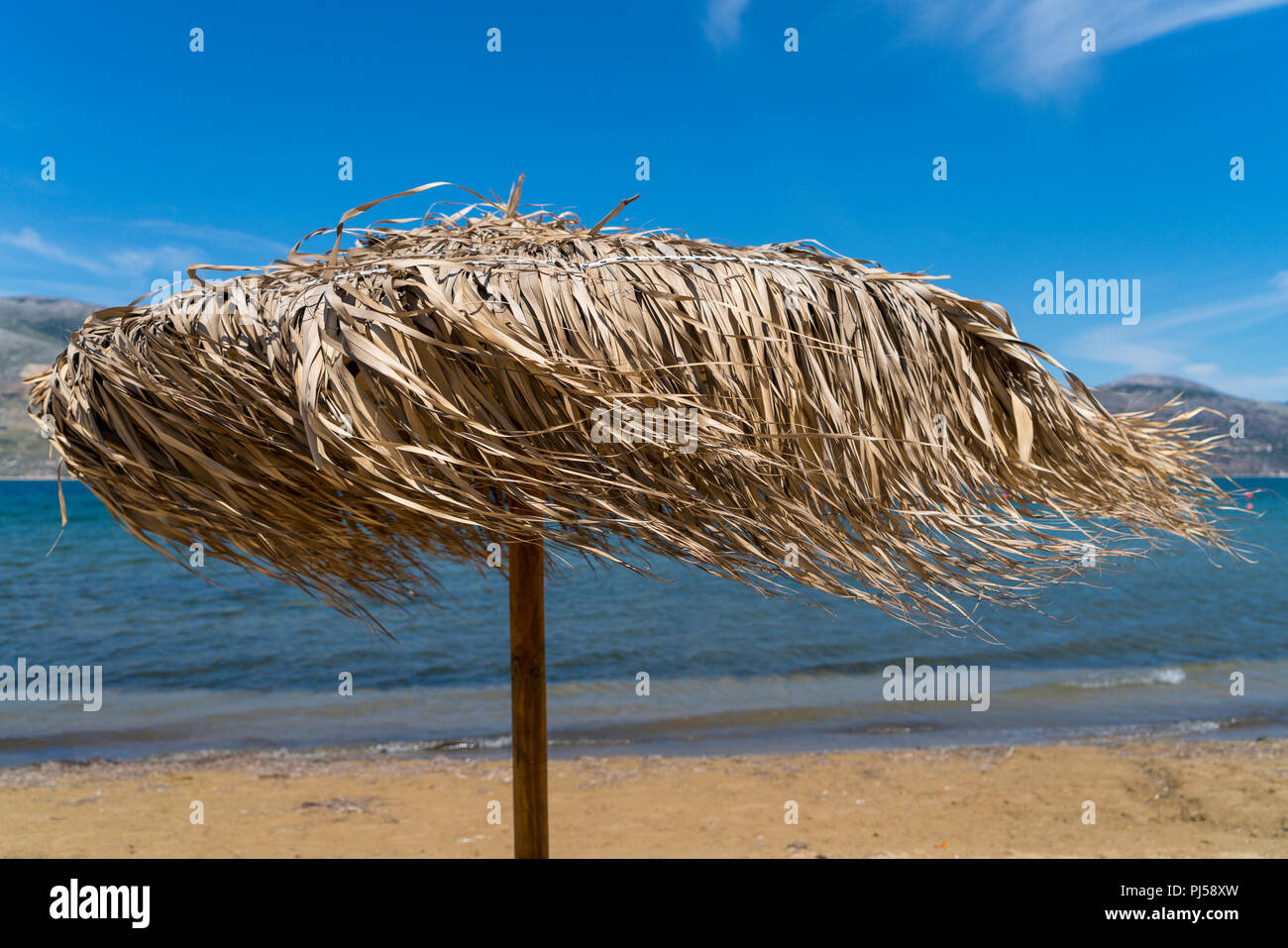 straw parasol, windy day on the beach Stock Photo - Alamy