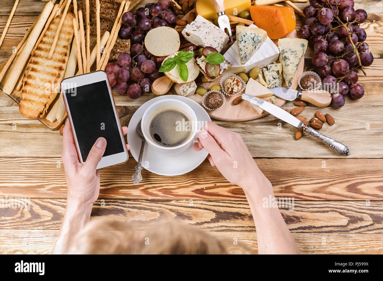 The woman is having breakfast. Female hands hold a cup of coffee and a ...