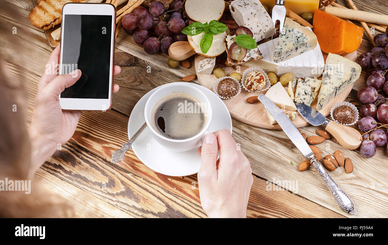 The woman is having breakfast. Female hands hold a cup of coffee and a ...