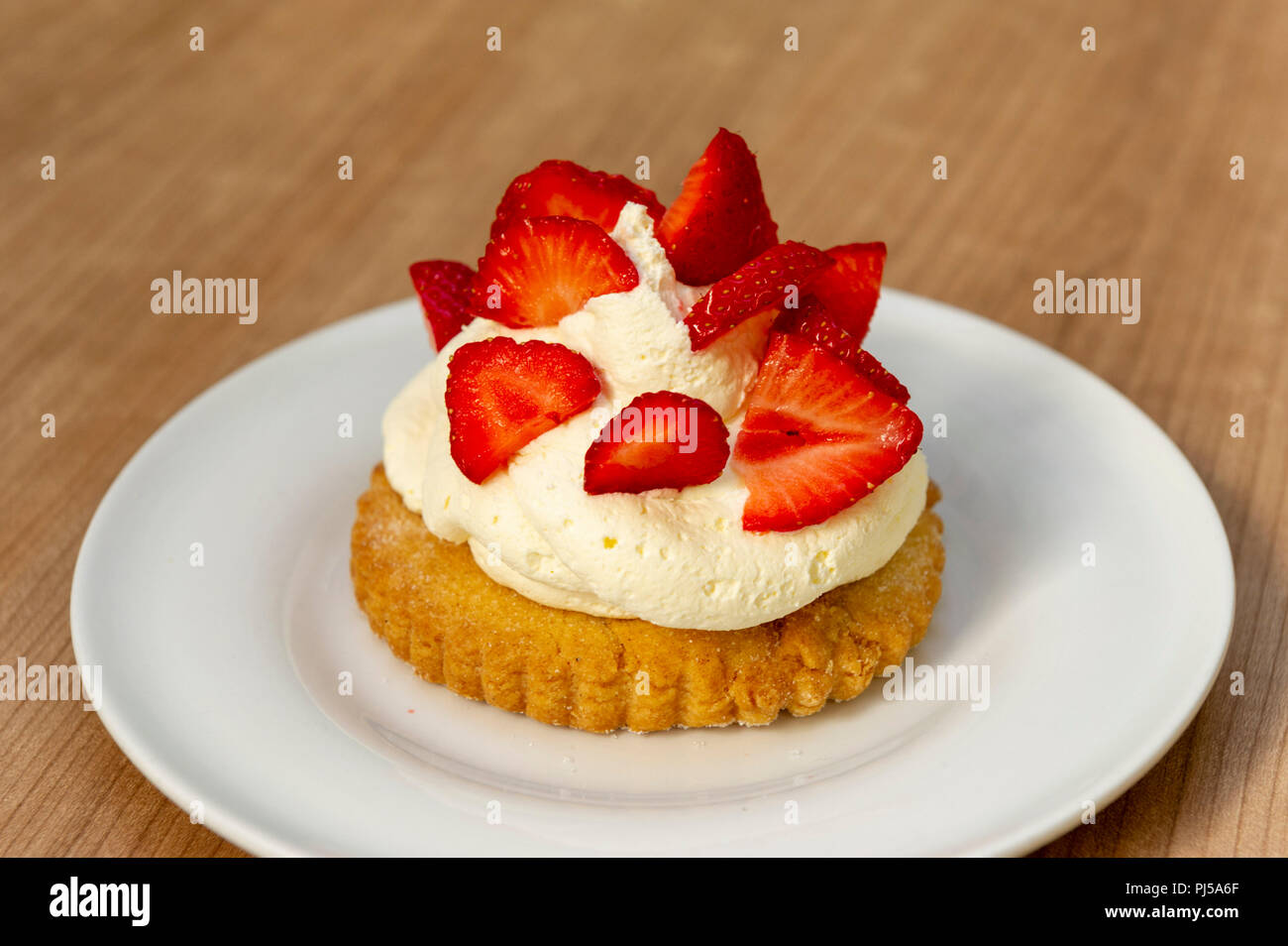 Strawberries and cream on shortbread biscuit on white plate Stock Photo ...