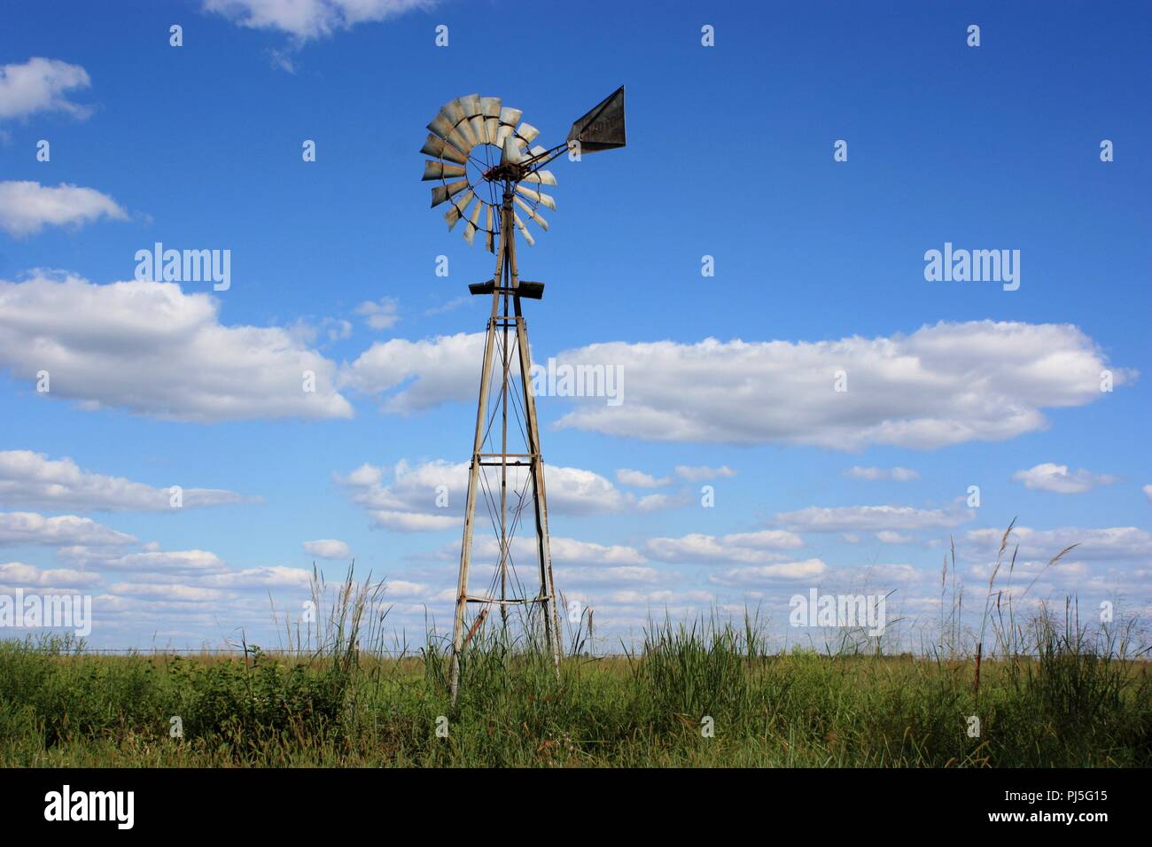 Windmill in a Pasture with green grass and blue sky Stock Photo - Alamy