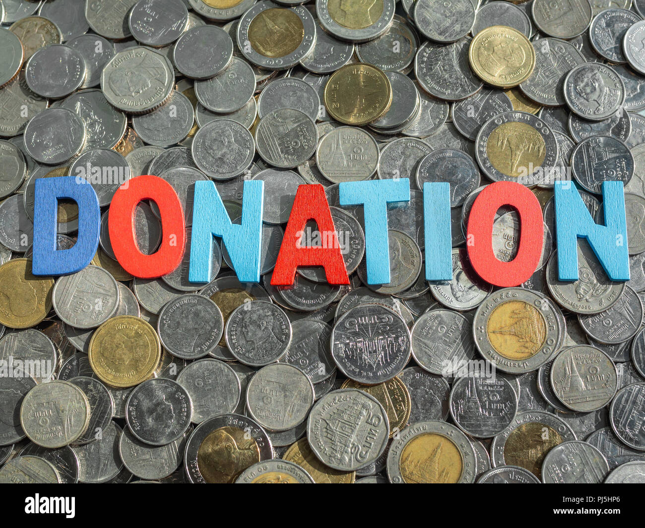 The word "Donation" in colorful alphabets onThai baht money coins ...