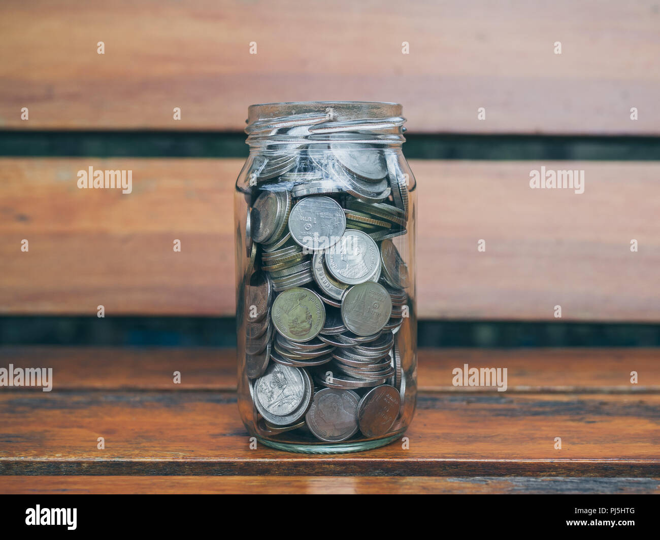 Coins in glass jar on wooden table background in. Saving money concept ...