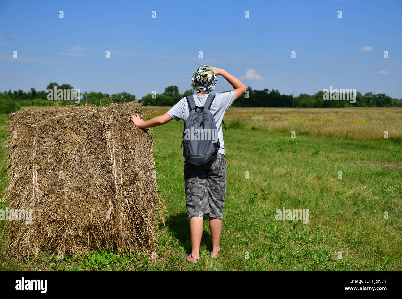 teen with backpack stands to stack of straw Stock Photo - Alamy
