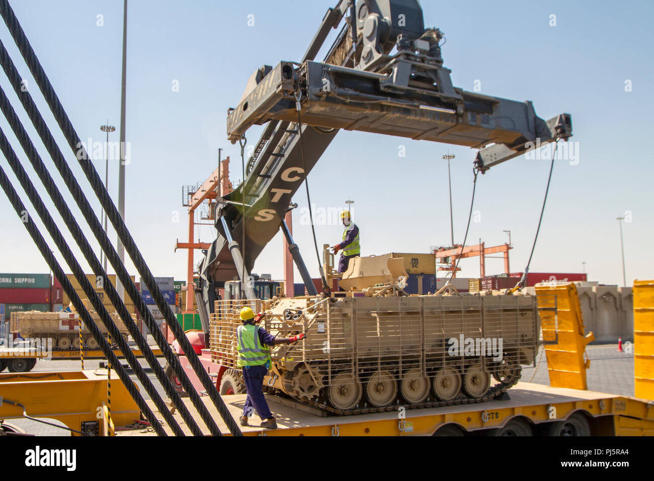 An M113 Armored Personnel Carrier is prepared to be loaded onto a barge ...
